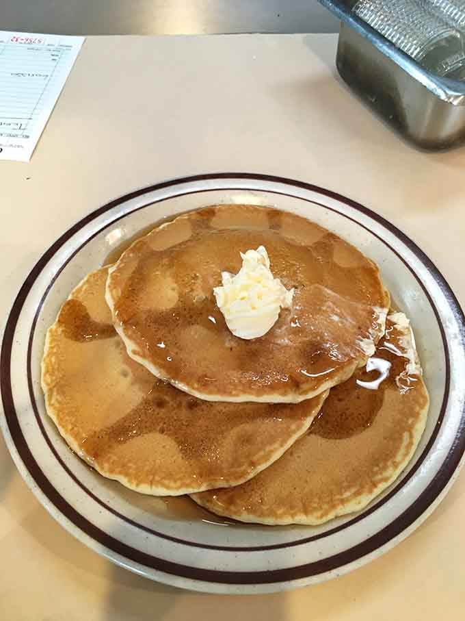 Fluffy pancakes stacked high with butter melting down like a delicious avalanche of morning happiness.