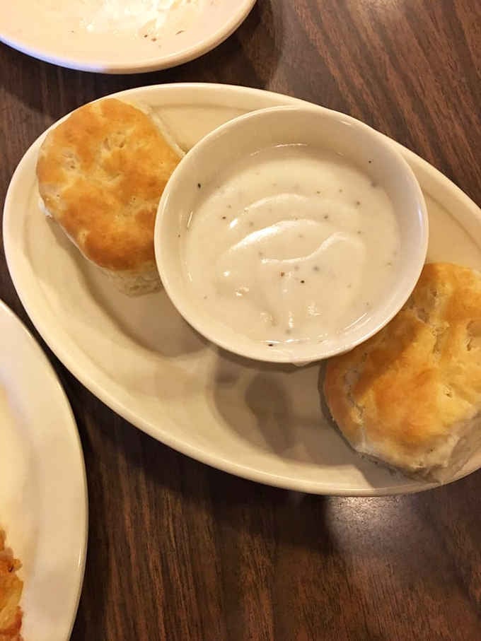Two fluffy biscuits drowning in peppery sausage gravy, because some mornings require serious comfort food intervention and zero apologies.