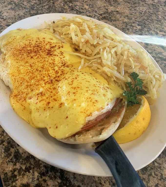 Eggs Benedict done right&mdash;hollandaise sauce cascading down like a yellow waterfall of breakfast bliss. Morning salvation on a plate.