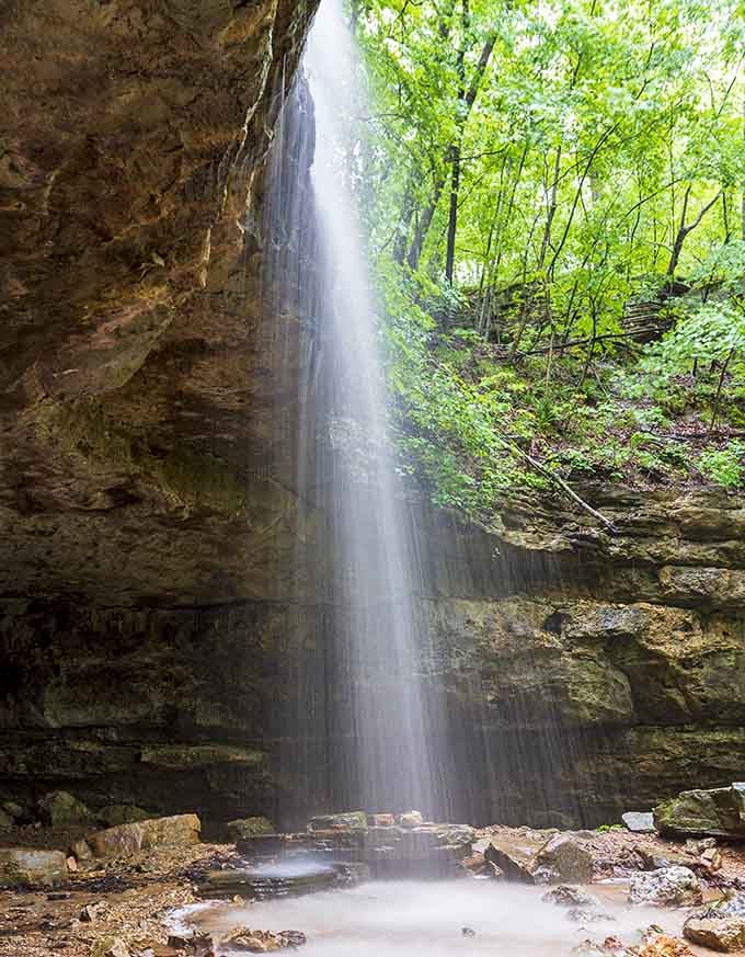 Water cascades down limestone cliffs, creating nature's own shower curtain in the Missouri wilderness.
