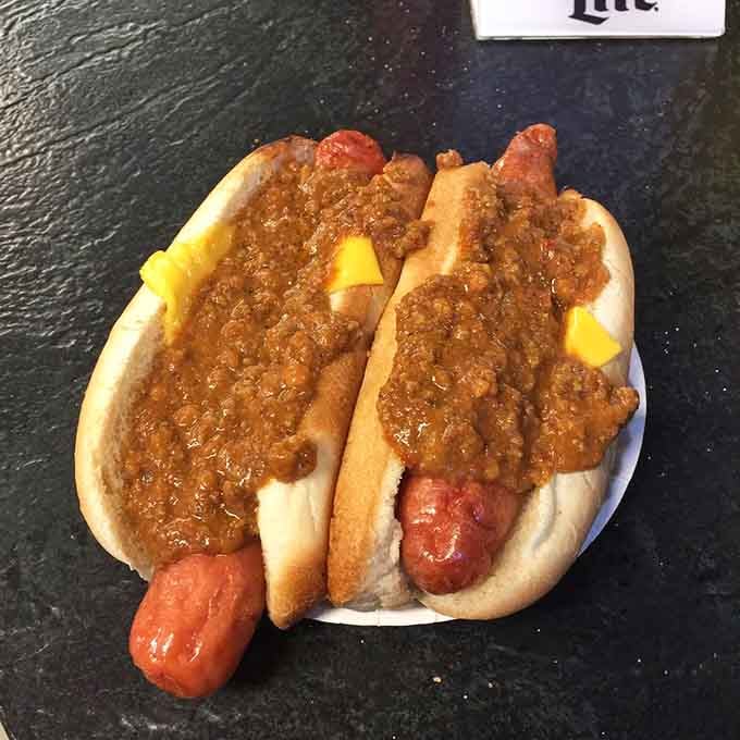 Two glorious dogs buried under a mountain of chili, because subtlety is overrated when you're this hungry.