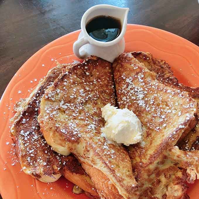 French toast dusted with powdered sugar like fresh snow, butter melting into golden, syrup-ready perfection waiting.
