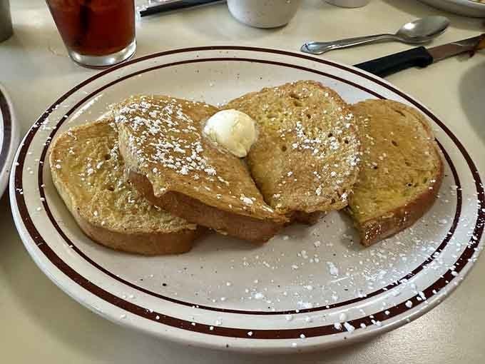 French toast dusted with powdered sugar like fresh snow on breakfast mountains, ready for that butter avalanche.