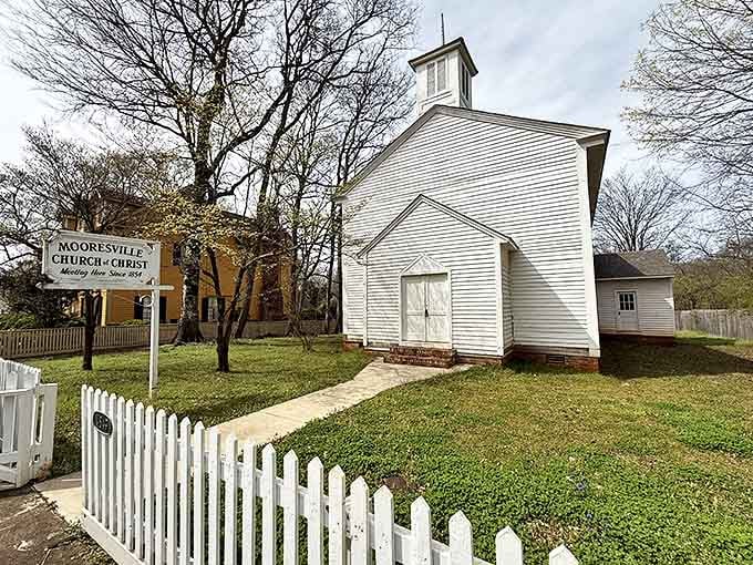 The white clapboard Church of Christ stands like a pristine wedding cake against Alabama's blue sky, picket fence included at no extra charge.