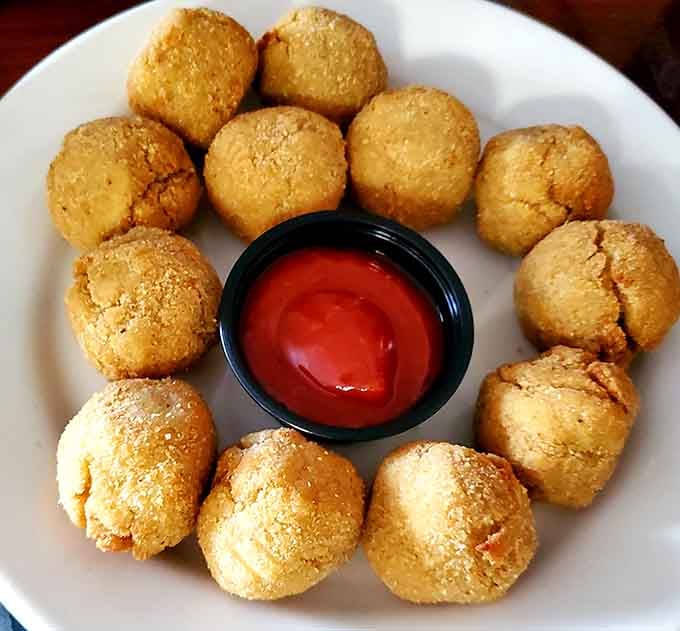 Golden crab balls circling cocktail sauce like they're protecting treasure, which honestly, they kind of are.