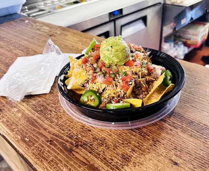 Nachos loaded with enough toppings to require architectural support, plus that perfect guacamole scoop on top.