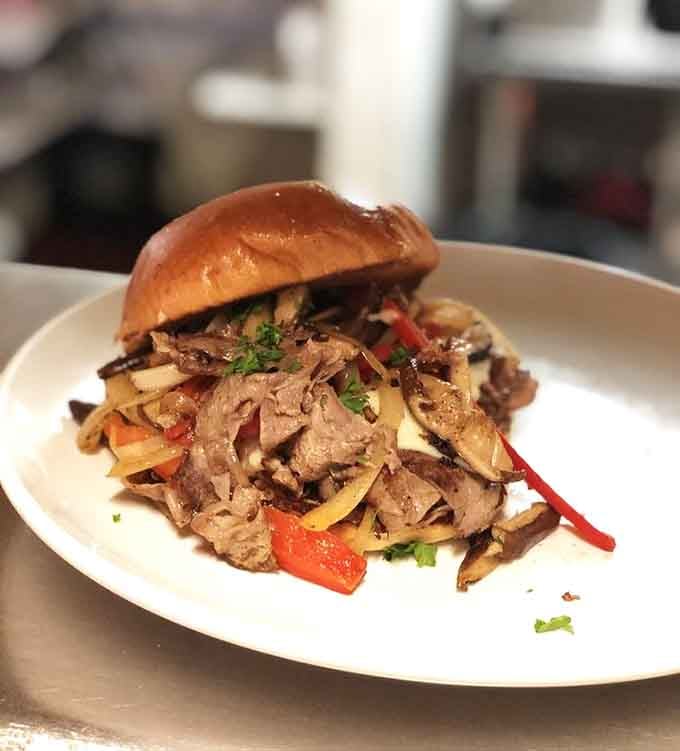 That roasted prime rib sandwich piled high with peppers and onions looks like it requires both hands and zero regrets.