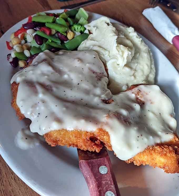 Country fried chicken smothered in gravy, served with sides that understand the assignment and then some.