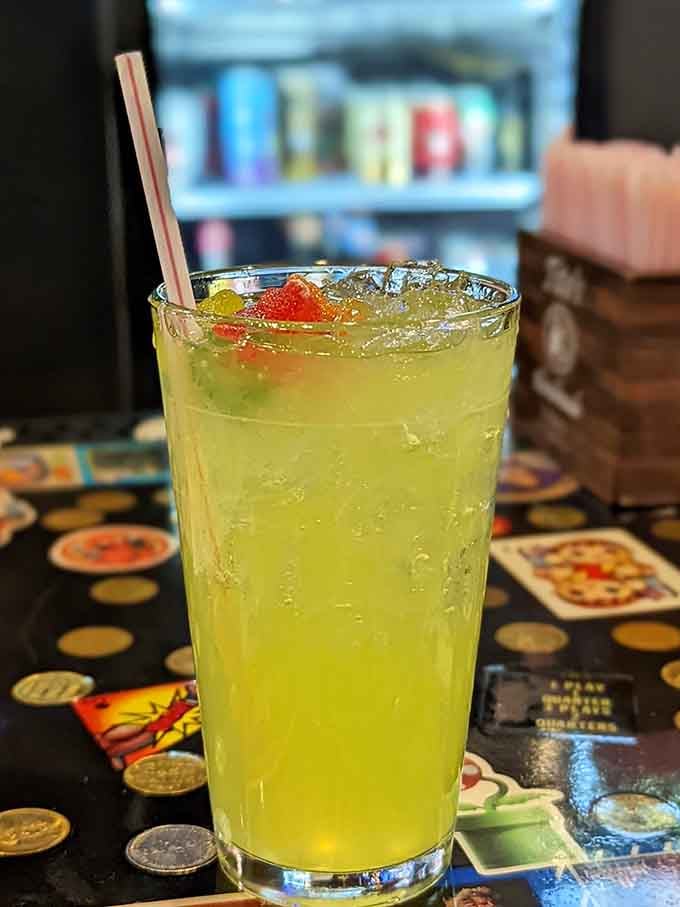 This citrus-bright refreshment sits ready on vintage arcade glass, cherries bobbing like power-ups in liquid form.