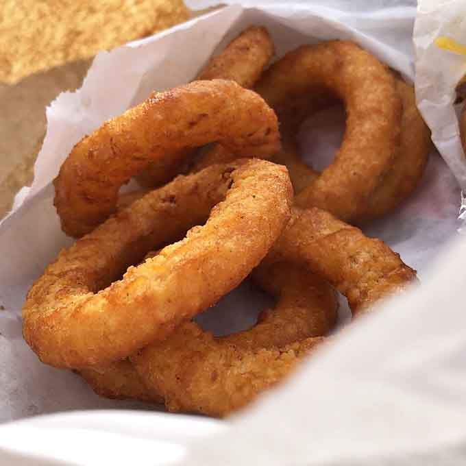 Golden onion rings so perfectly circular they could double as Olympic medals for people who appreciate fried food done right.