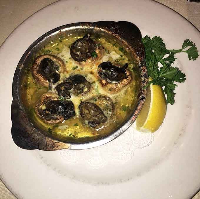 Escargot swimming in garlic butter, looking like tiny flavor bombs ready to explode on your taste buds delightfully.