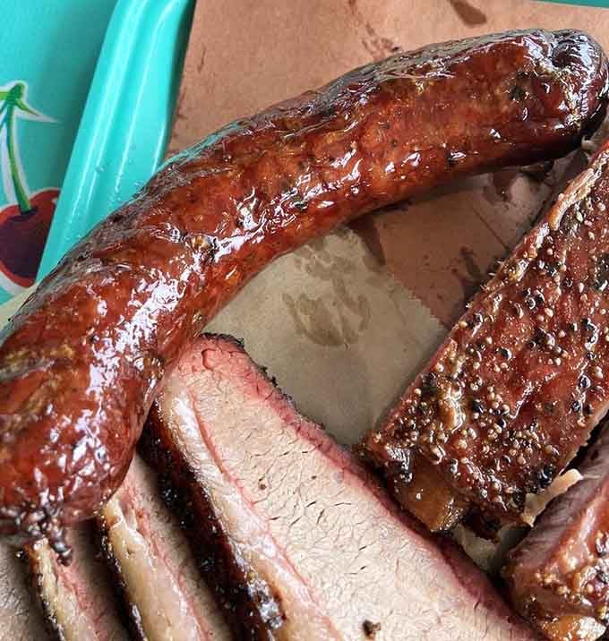 Perfectly glazed sausage and sliced brisket with that telltale smoke ring showcase true barbecue craftsmanship here.