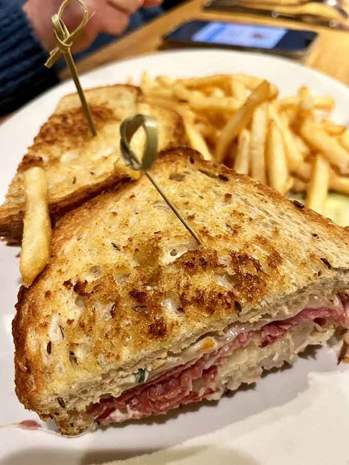 That Reuben sandwich stacked high with corned beef, showing proper respect for a deli classic done right every time.