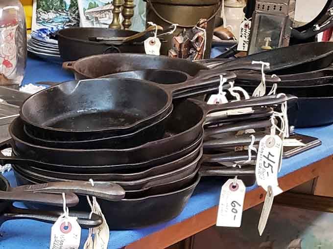 Cast iron skillets stacked like black gold. These kitchen workhorses have probably flipped more pancakes than IHOP on a Sunday morning.