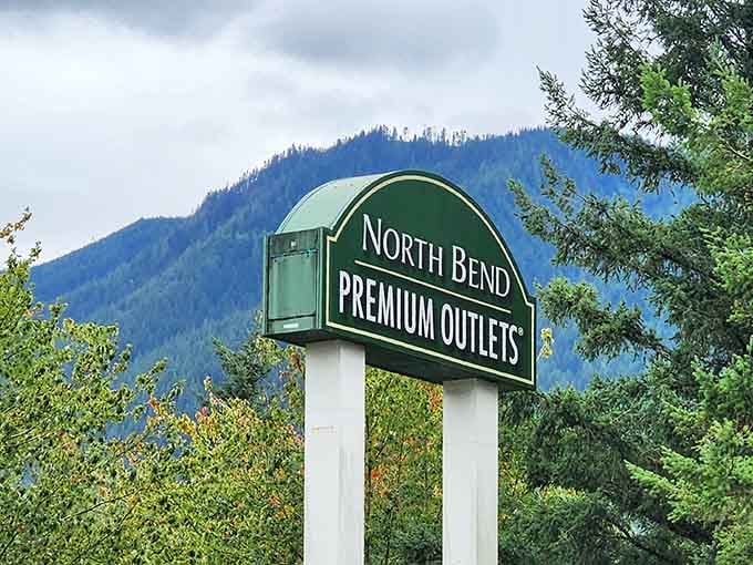 That green sign against blue sky promises savings so good, even the mountains pause to take notice.