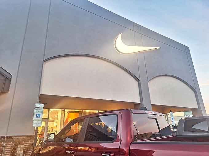 The iconic Nike swoosh glows like a retail lighthouse, beckoning shoppers toward athletic aspirations and the strange joy of spending less on overpriced sneakers.