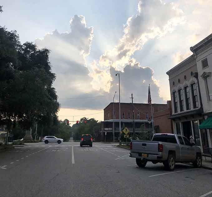 Bright clouds paint the sky in dramatic swirls, while historic buildings stand silhouetted like patient sentinels.