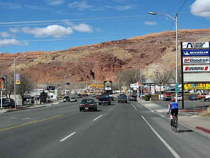 Moab's main drag cuts through town with red rock formations creating a dramatic backdrop that no city planner could design.
