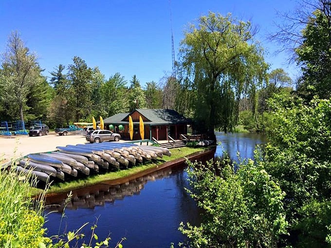 Canoes line the riverbank like colorful candies, ready to carry adventurers downstream through Michigan's peaceful north woods.