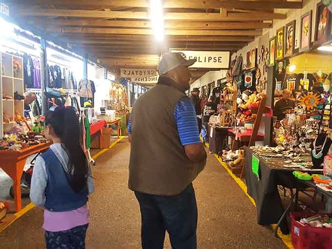 Vintage collectibles line tables while shoppers browse thoughtfully, each item holding stories from someone's cherished past waiting for new homes.