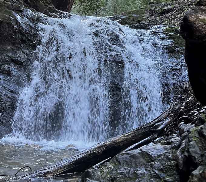 The powerful cascade spreads wide across colorful stone, showing off like a peacock displaying its most impressive feathers proudly.