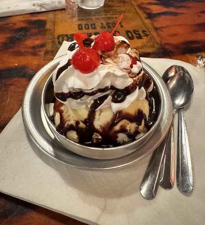 An ice cream sundae topped with enough whipped cream and cherries to make your dentist schedule a follow-up appointment.