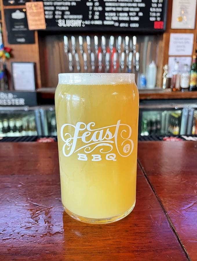 Cold craft beer in a branded glass, because smoked meat deserves a proper drinking companion.