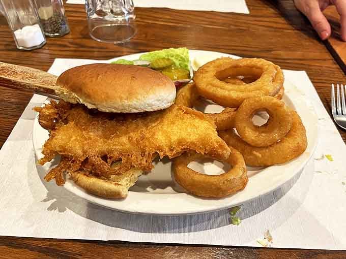 Golden-battered fish sandwich with onion rings that form perfect halos. This plate doesn't just satisfy hunger &ndash; it creates memories.
