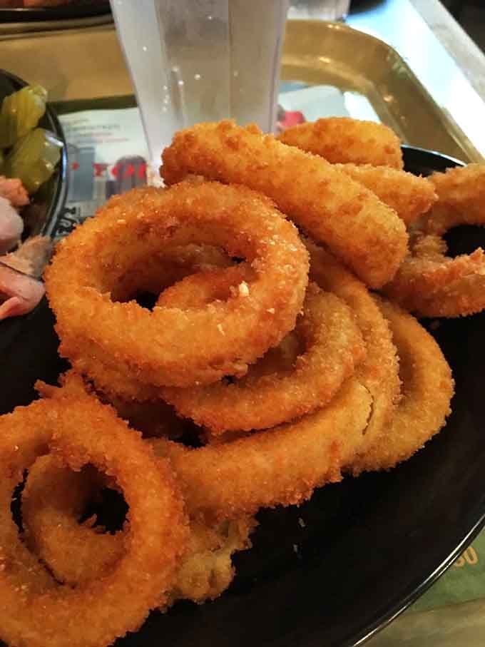 Golden onion rings stacked like edible poker chips, crispy and ready for their sauce-dipping destiny.