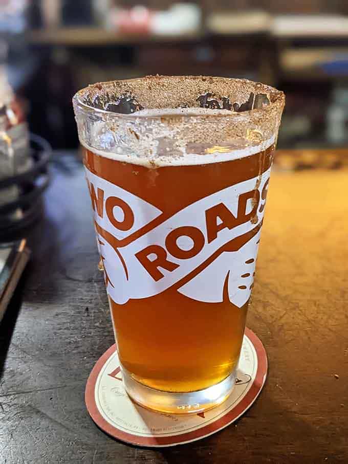 Cold beer in a frosted glass with a "No Roads" coaster, the simple pleasures hitting different today.