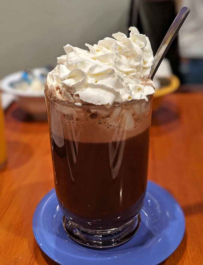 Hot chocolate topped with whipped cream that's taller than some small buildings, because moderation is overrated at breakfast.