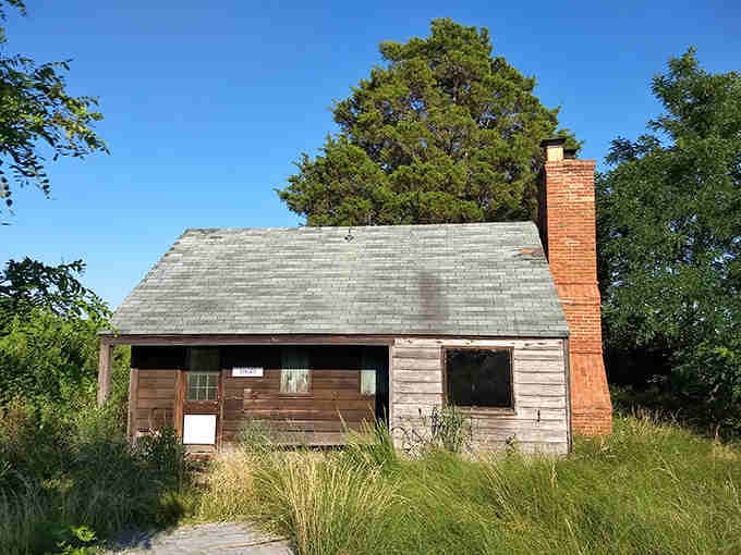 A weathered historic structure standing quietly in the grass, patiently waiting to tell its story to passing visitors.
