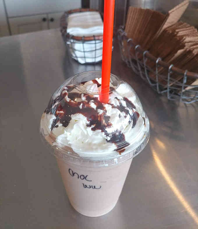 A chocolate shake topped with whipped cream and chocolate drizzle, because sometimes subtlety is overrated and happiness is mandatory.