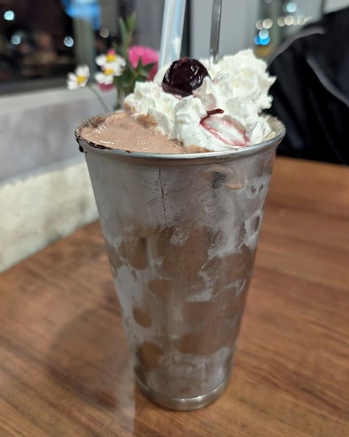 That chocolate shake topped with whipped cream and a cherry is basically childhood in a glass, improved.