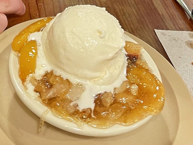 Peach cobbler topped with vanilla ice cream, because apparently they want you to leave here smiling forever.