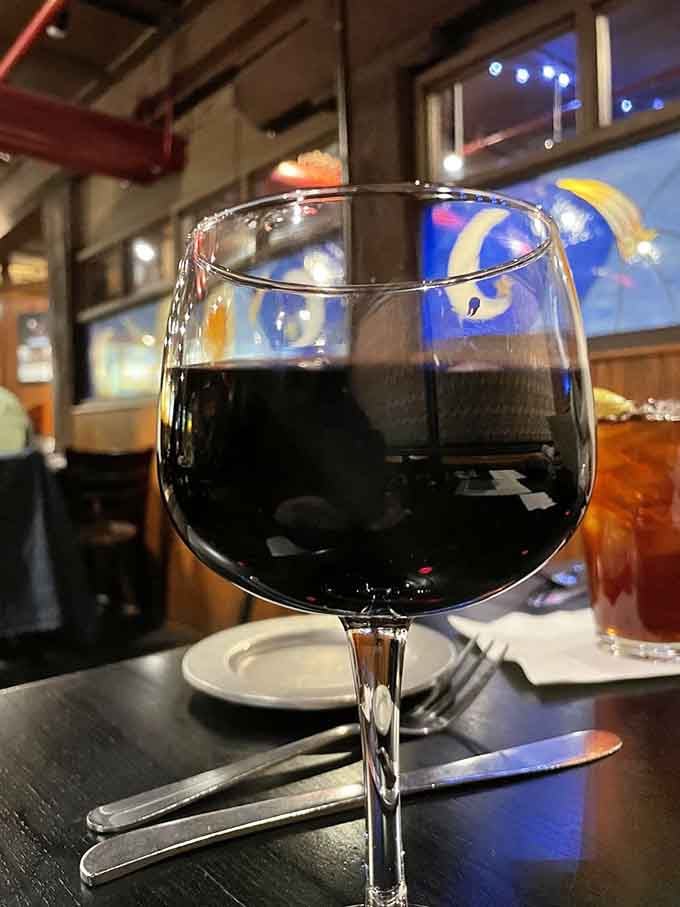 A glass of Pinot Noir catching the light, because even barbecue joints know how to set the mood right.