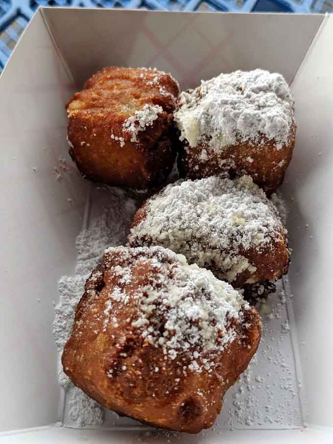 Four golden banana bites dusted with powdered sugar represent the kind of dessert that makes diet plans weep quietly.