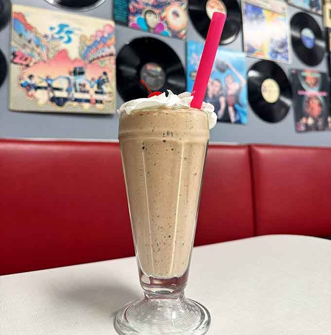 This milkshake sits in a classic fountain glass, thick enough to require strategic spoon-and-straw coordination for maximum enjoyment.