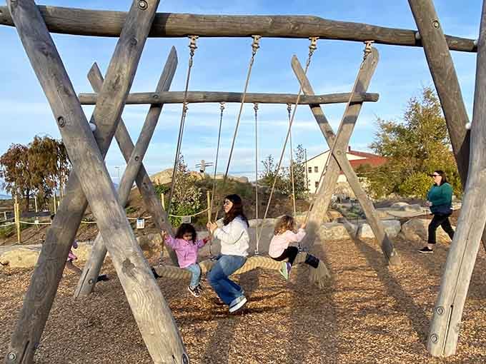 Kids swinging with bay views behind them, living childhood better than most adults are living their actual lives right now.
