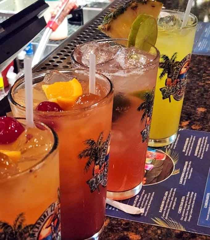 Tropical drinks in souvenir glasses: because sometimes adulting requires colorful beverages with tiny umbrellas and zero apologies.