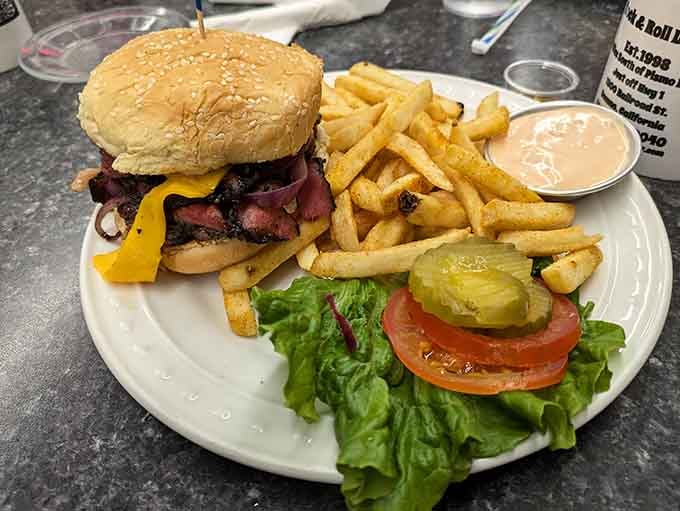 This burger towers with confidence, stacked high with toppings that would make any drive-in movie proud back then.
