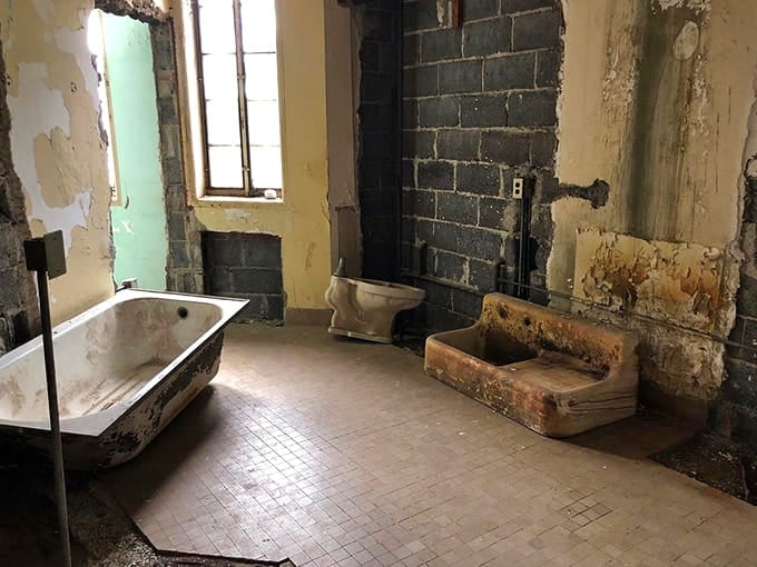 The deteriorating bathroom fixtures and crumbling walls create an atmosphere that's equal parts historical preservation and horror movie set.