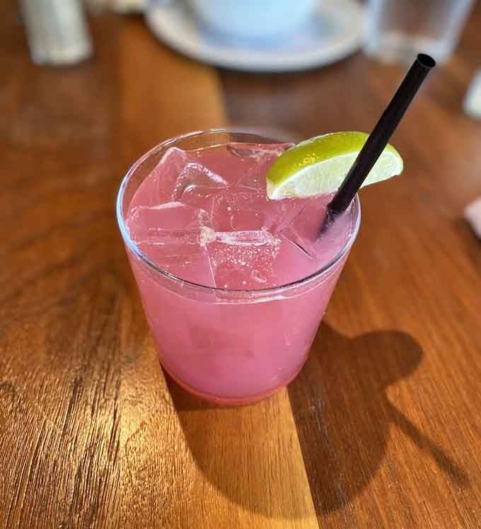 A refreshing pink cocktail with lime garnish, because sometimes the best seafood companion comes in a frosty glass with a straw.