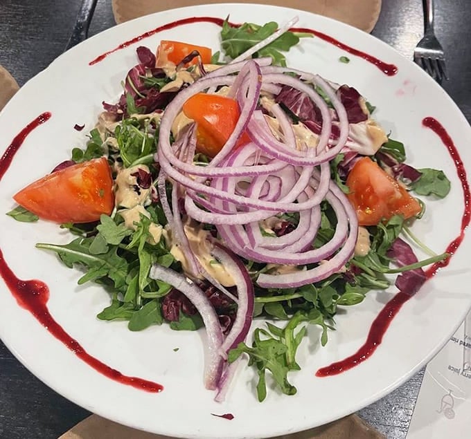 Fresh greens get the gourmet treatment with vibrant tomatoes and artistic drizzles that make salad feel like celebration food.