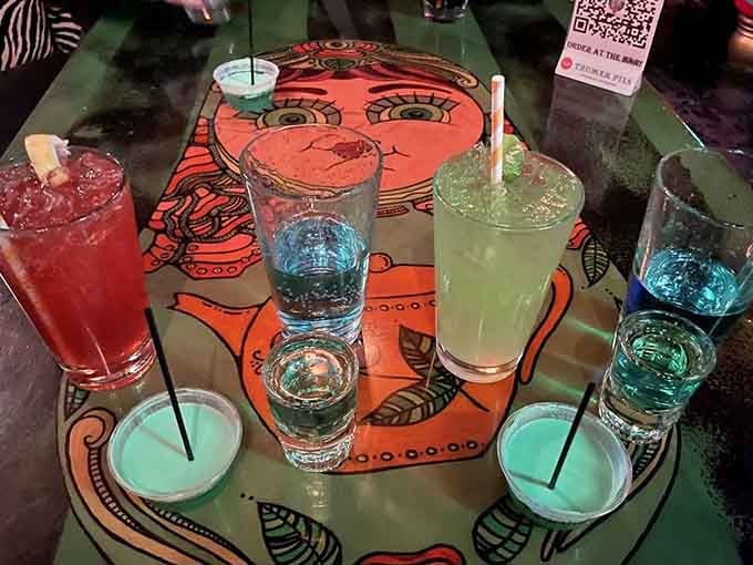 Colorful cocktails served on tables decorated with faces, making your drinks feel like part of the art.