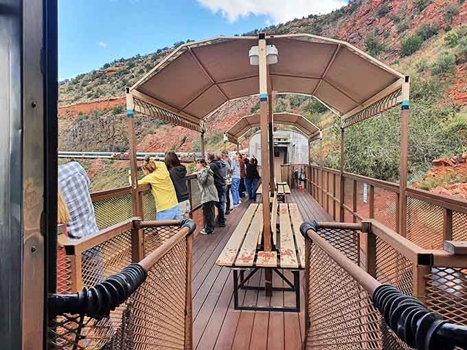 The canopied platform provides shade while you watch red rocks rise dramatically behind the waiting train cars.