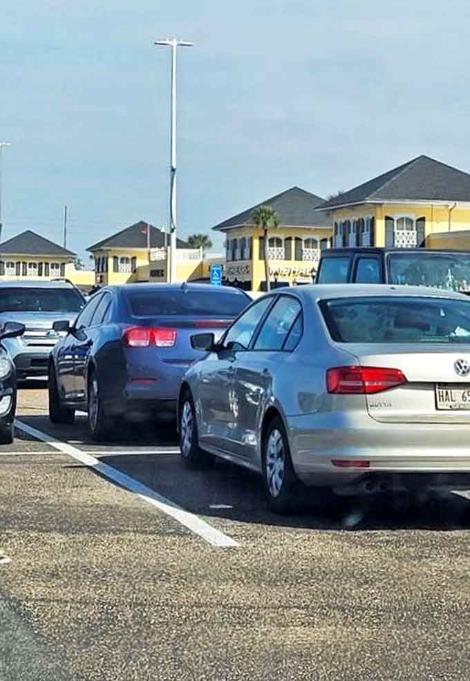 Cars line up like eager shoppers, everyone positioning for the closest spot to maximize carrying capacity for the journey home. The yellow buildings beckon with promises of retail therapy.