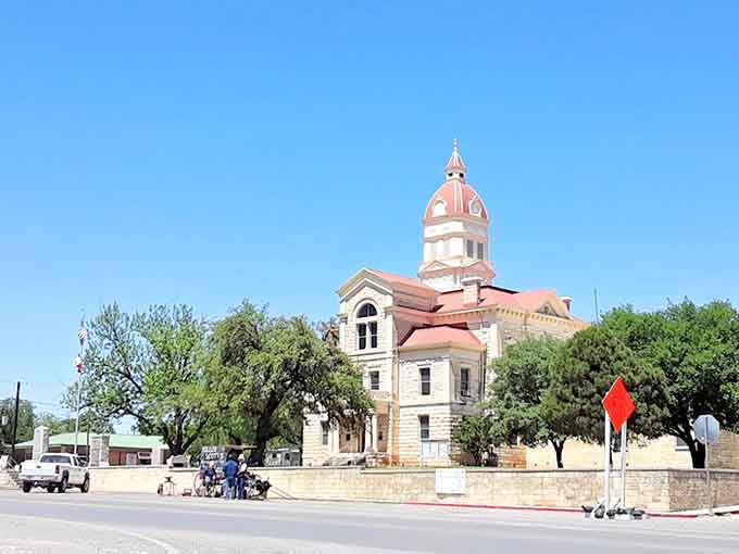 The pink-domed courthouse rises majestically, a beacon of history surrounded by protective trees and endless summer sky.