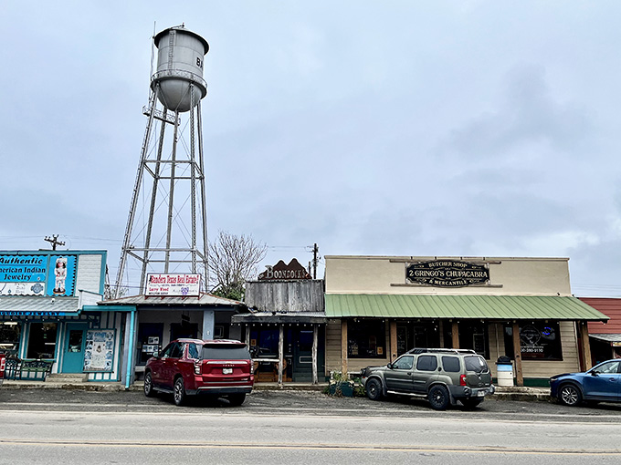 That water tower stands sentinel over authentic storefronts where real cowboys still shop for boots and necessities daily.