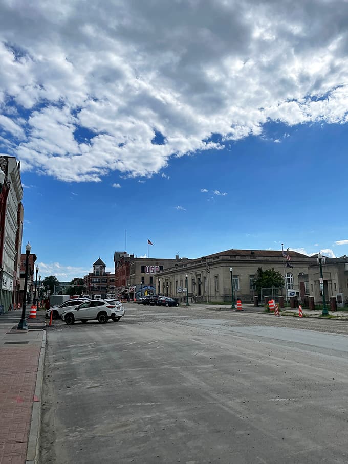 Wide open streets under dramatic clouds showcase classic downtown buildings that have weathered many seasons with grace.